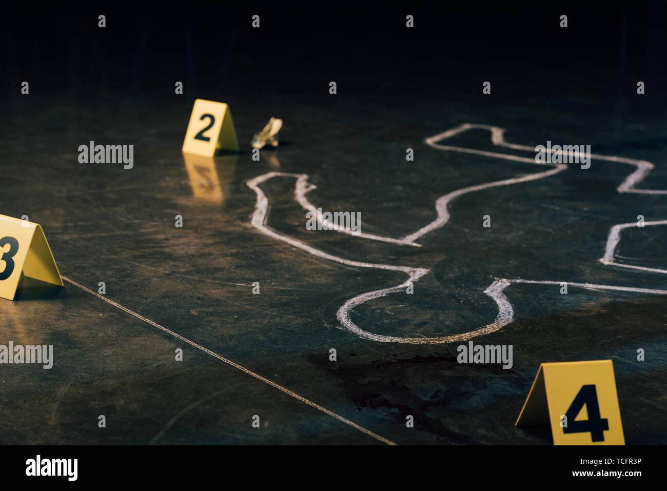 selective focus of chalk outline and evidence markers at crime scene ...