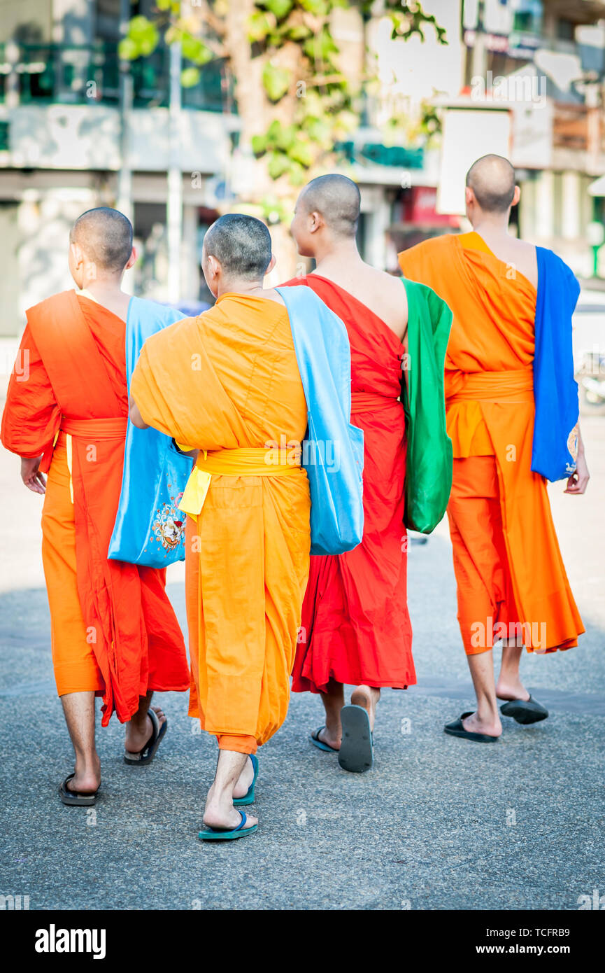 Thai monks make their way across the road to a local temple or Wat in ...