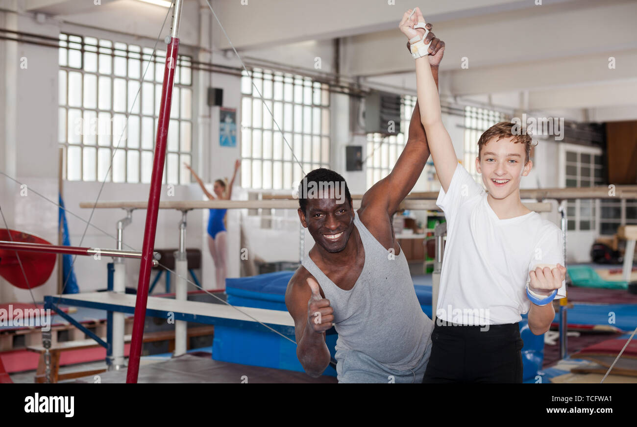 Male coach trainer and teenage athlete exulting sporting achievements ...