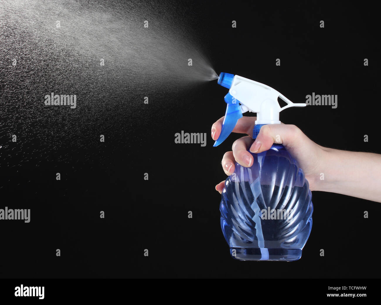 hand holding spray bottle and spraying on black background Stock Photo ...