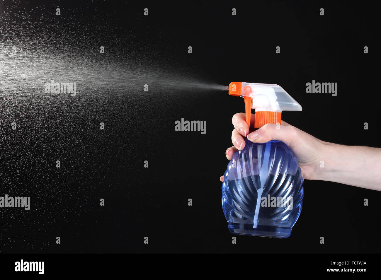 hand holding spray bottle and spraying on black background Stock Photo ...