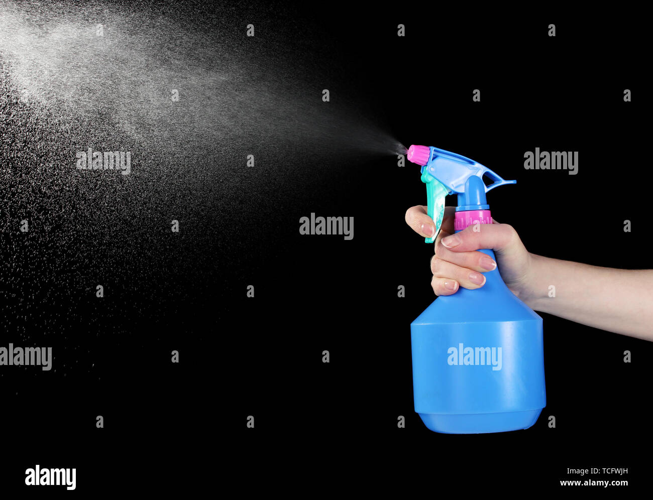 hand holding spray bottle and spraying on black background Stock Photo ...