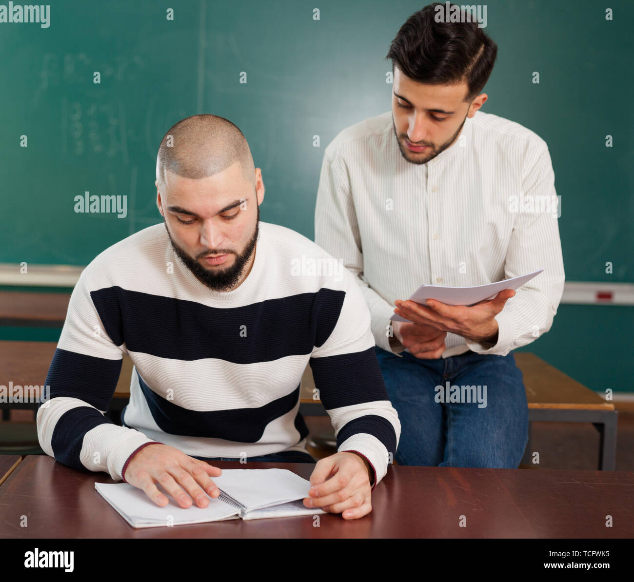 Portrait of two young guys working on their student project at desk in ...