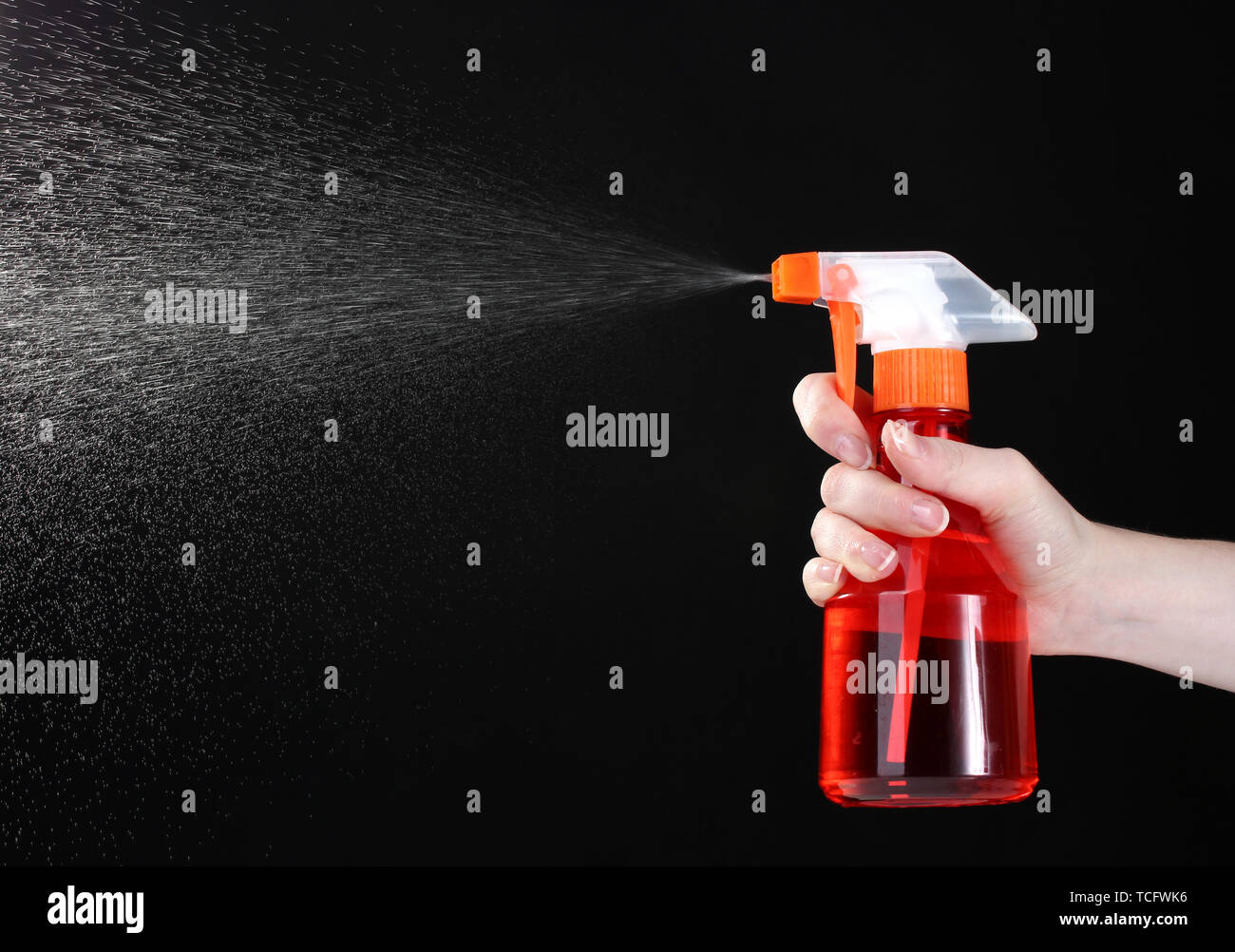 hand holding spray bottle and spraying on black background Stock Photo ...