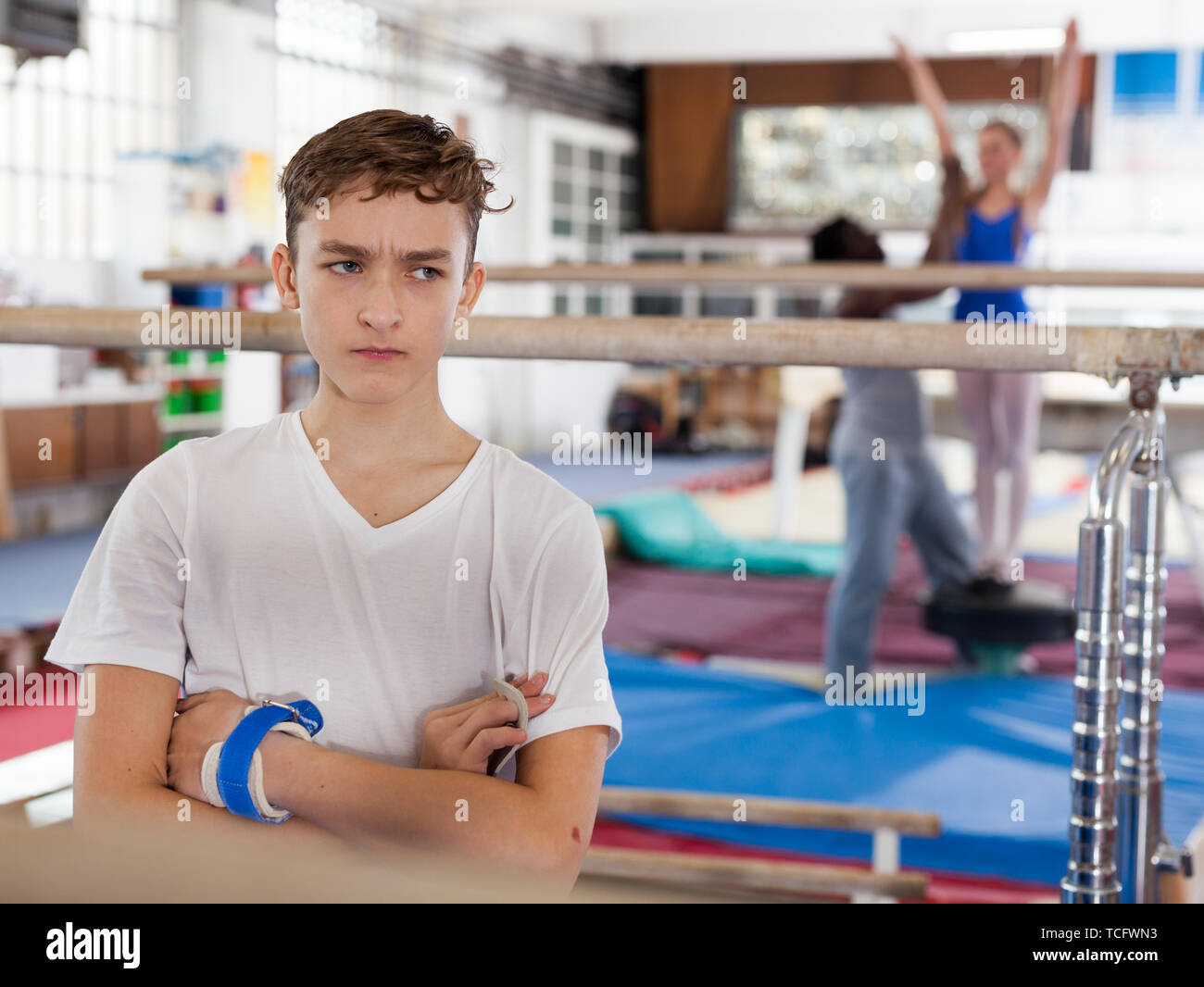 Portrait of sad teenage athlete standing near gymnastic equipment at ...