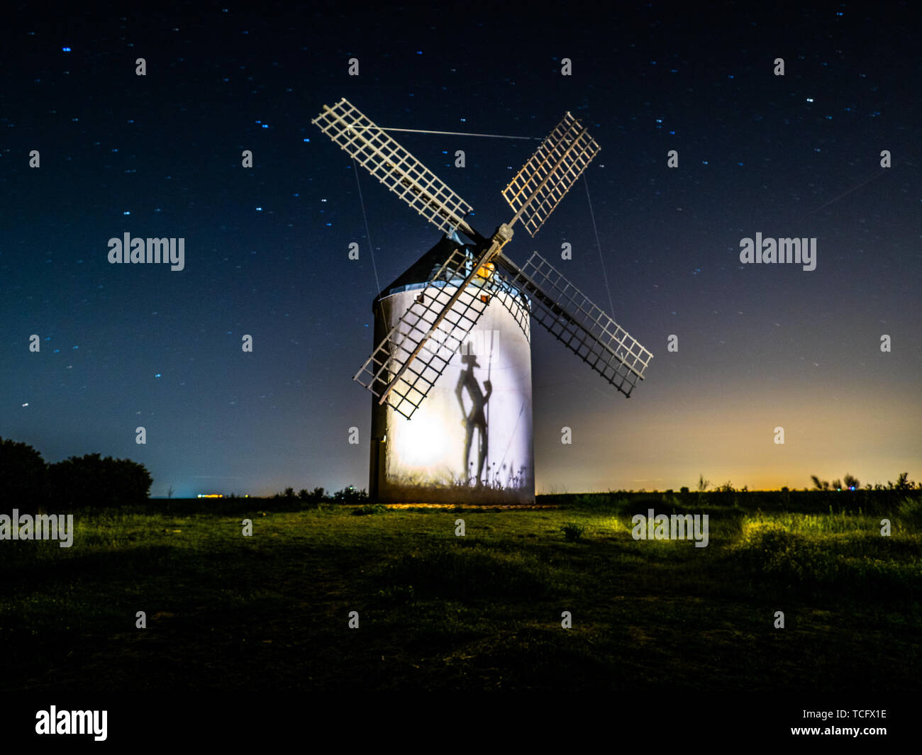Night photograph of a windmill with the silhouette of don Xijote making ...