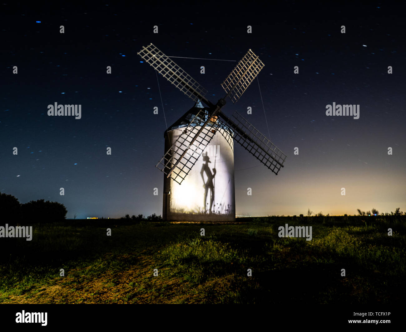 Night photograph of a windmill with the silhouette of don Xijote making ...