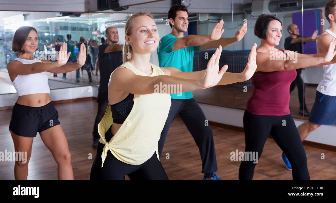 Positive people exercising zumba elements together in dancing hall ...