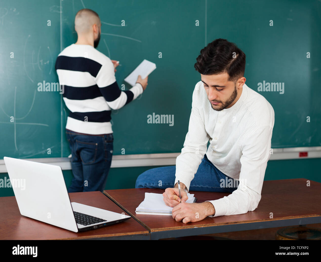 Portrait of two young guys working on their student project near ...