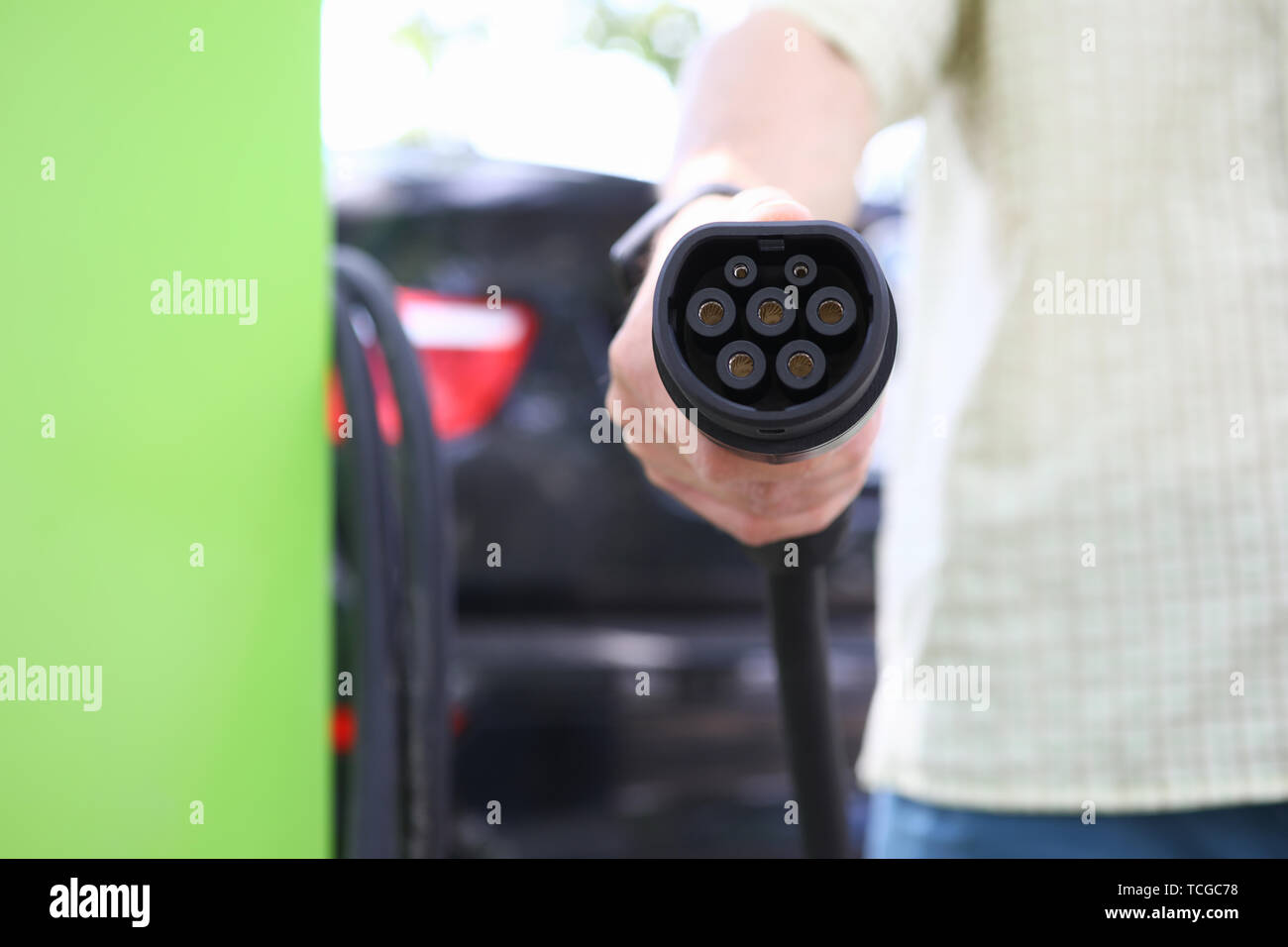 Male hand holding black car charging car cable Stock Photo - Alamy