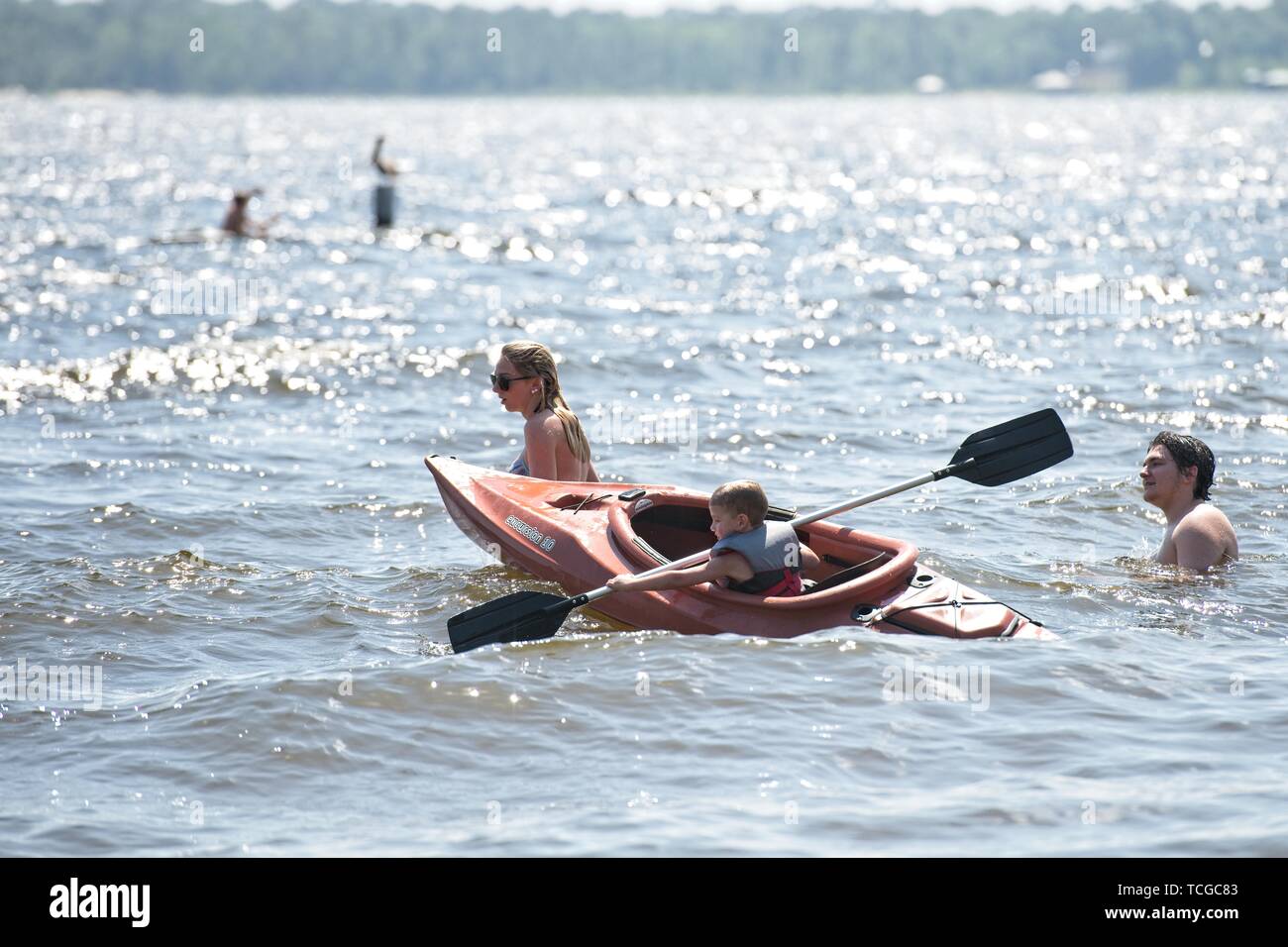 A teenage girl and boy play in the water while their young brother ...