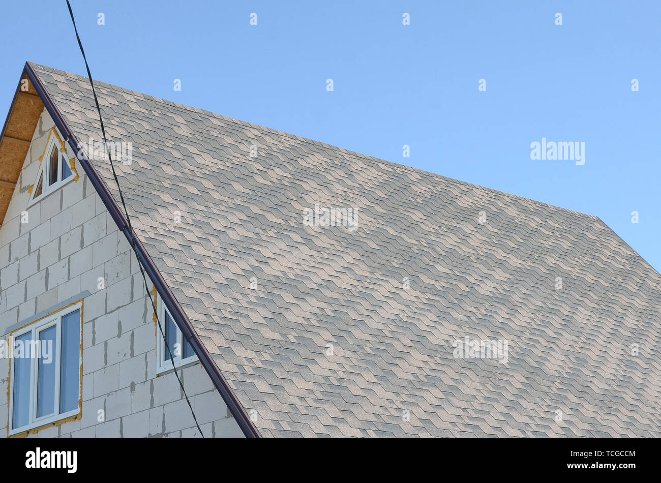 Flexible shingles of bitumen roofing surface on the brick house. Mosaic ...
