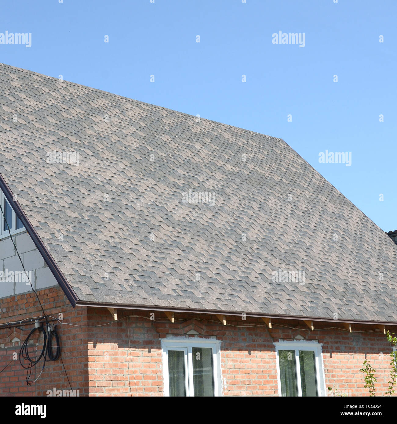 Flexible shingles of bitumen roofing surface on the brick house. Mosaic ...