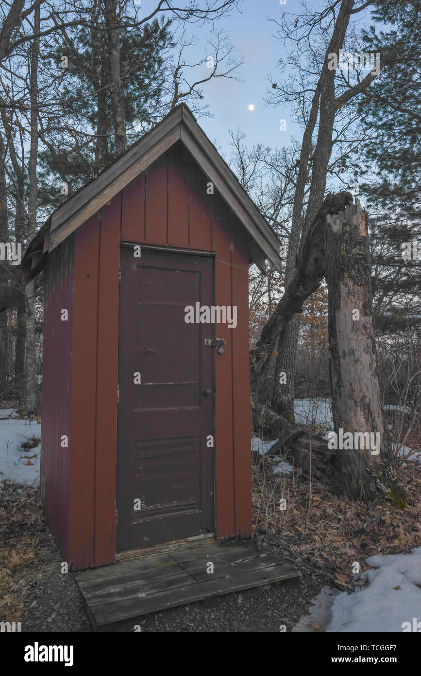 Red abandoned outhouse in the woods under the moon and moonlight at ...