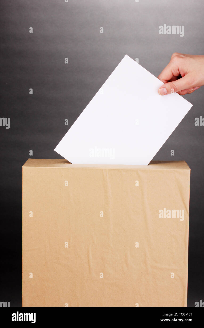 Hand with voting ballot and box on grey background Stock Photo - Alamy