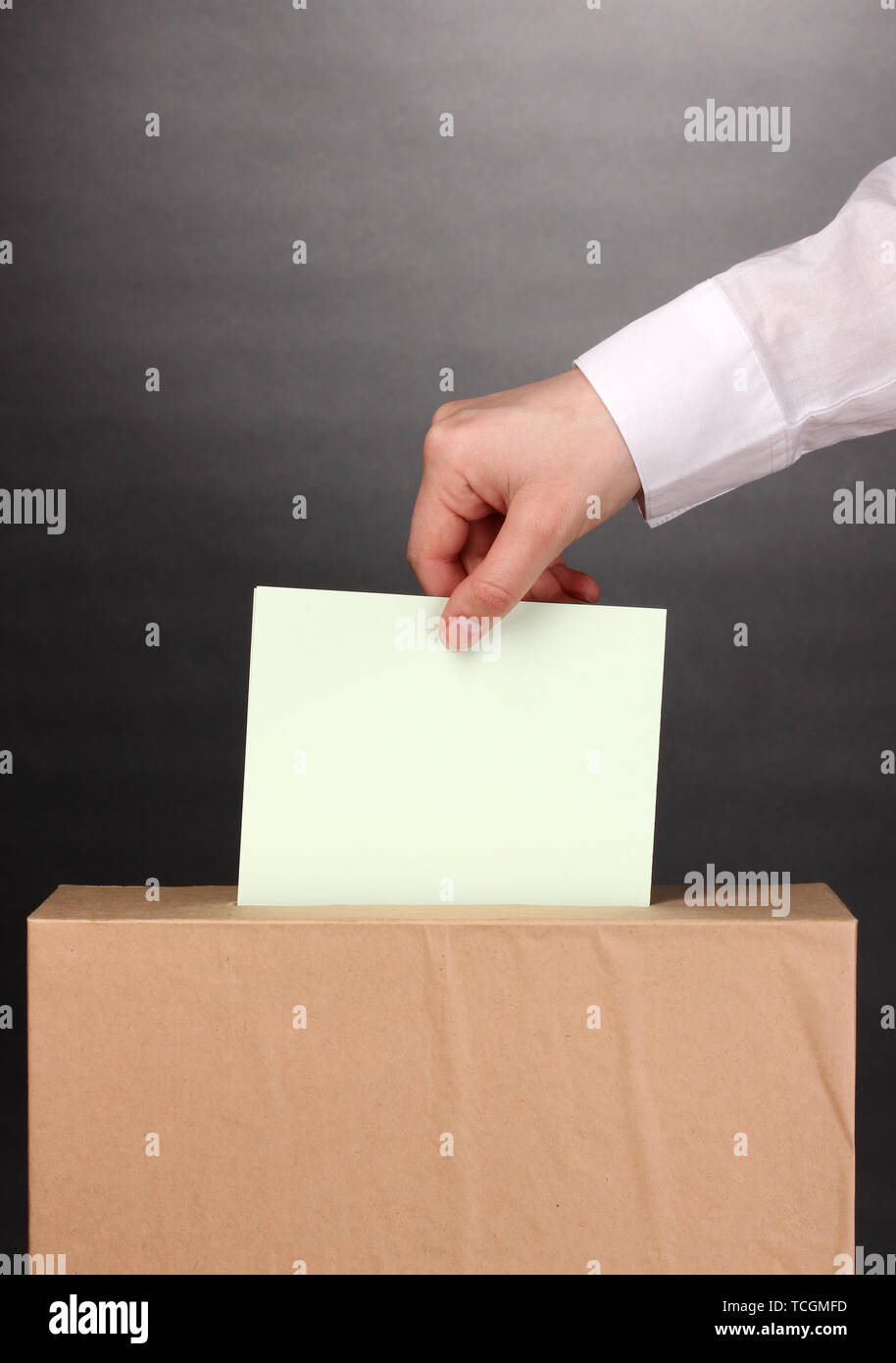 Hand with voting ballot and box on grey background Stock Photo - Alamy