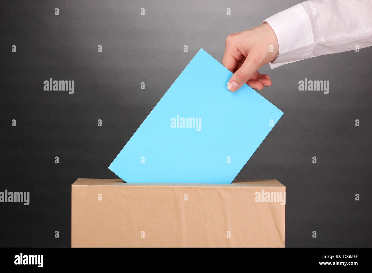 Hand with voting ballot and box on grey background Stock Photo - Alamy