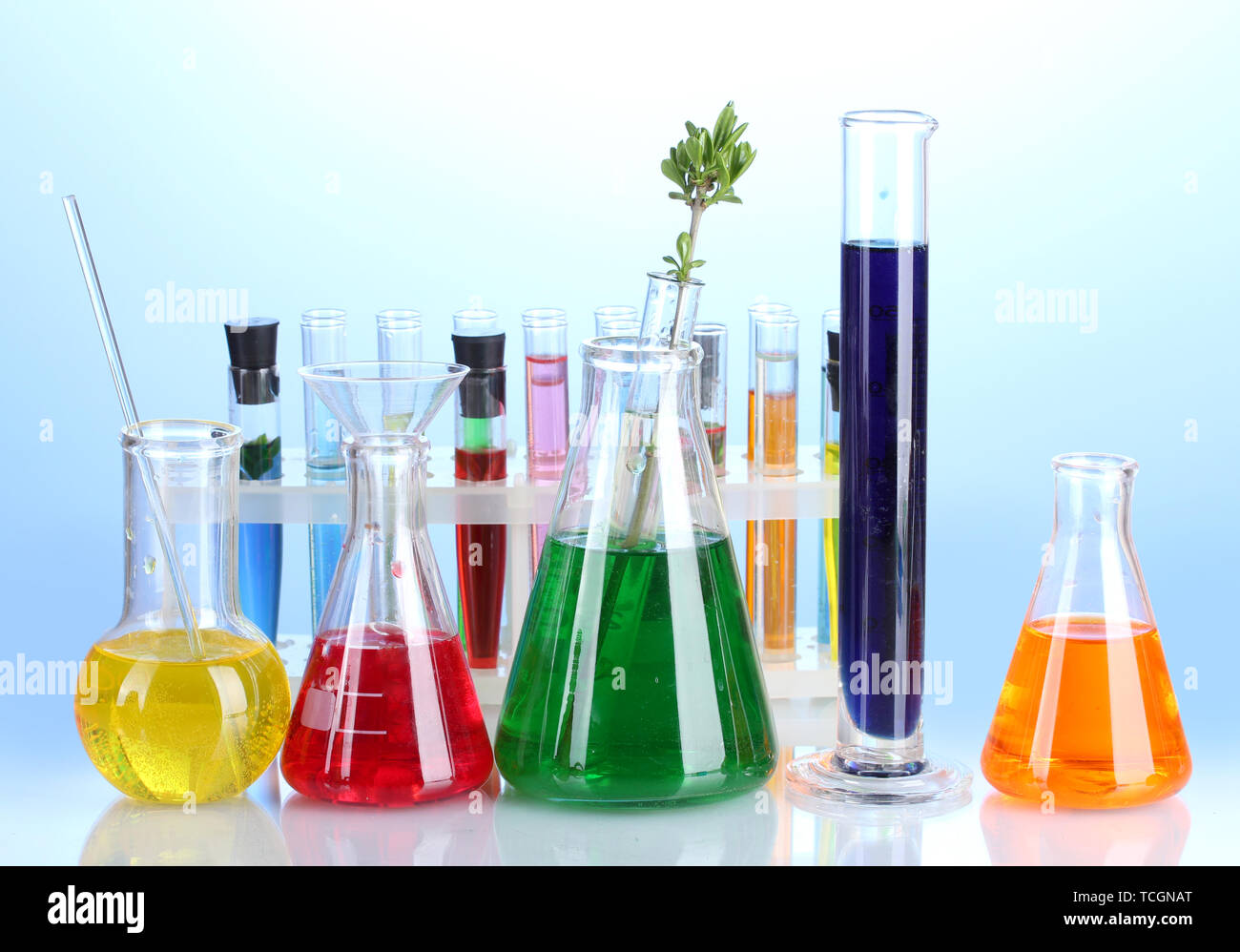 Different laboratory glassware with color liquid on blue background ...