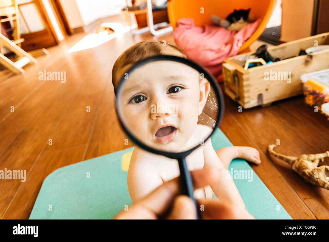 Baby face while playing with a magnifying glass, which makes a funny ...
