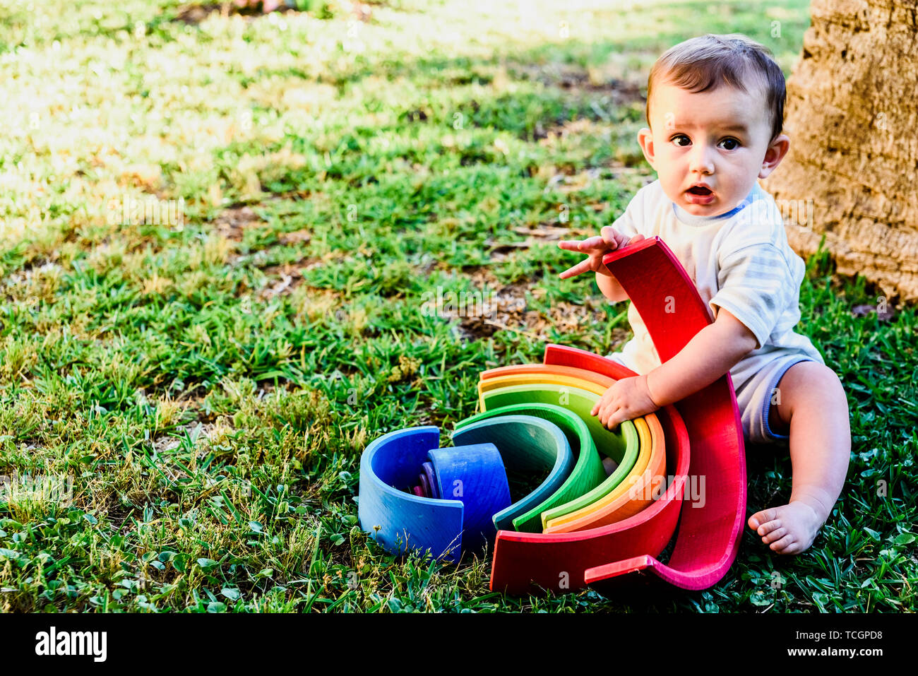 Baby playing with a colorful wooden rainbow on the grass, children's ...