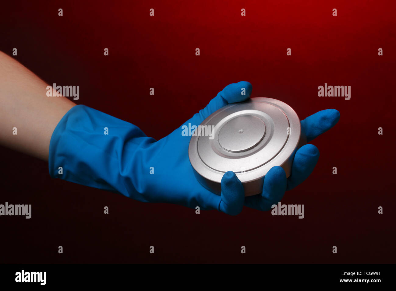 Uranium in hand on red background Stock Photo - Alamy