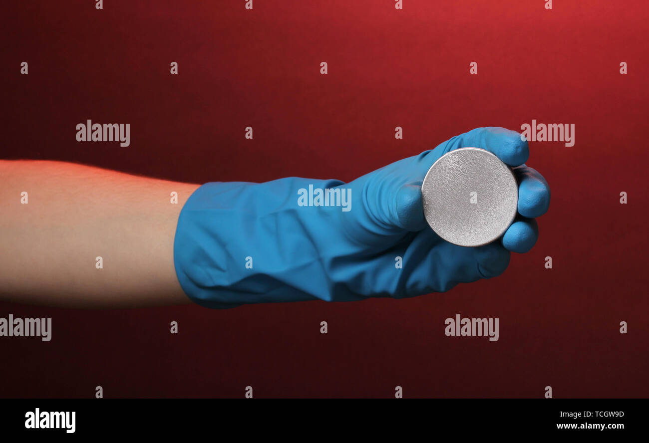 Uranium in hand on red background Stock Photo - Alamy