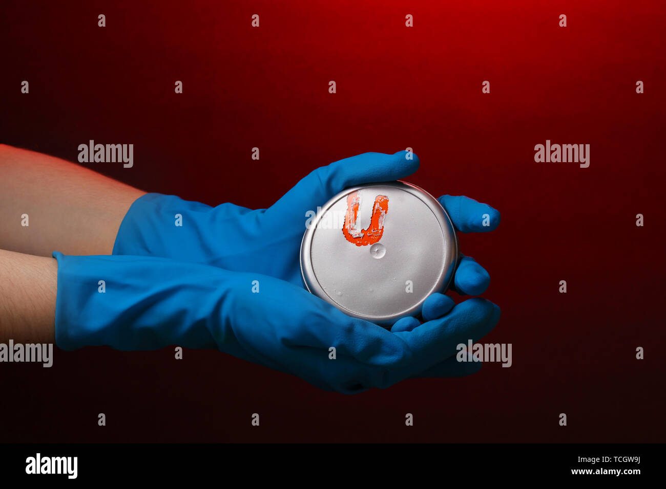 Uranium in hands on red background Stock Photo - Alamy