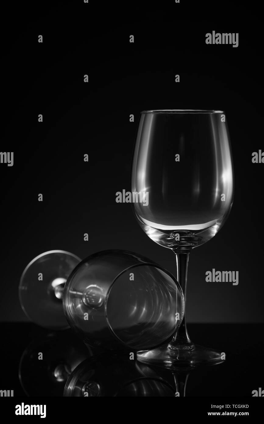 One wine glass is standing empty and upright, other is empty fallen ...