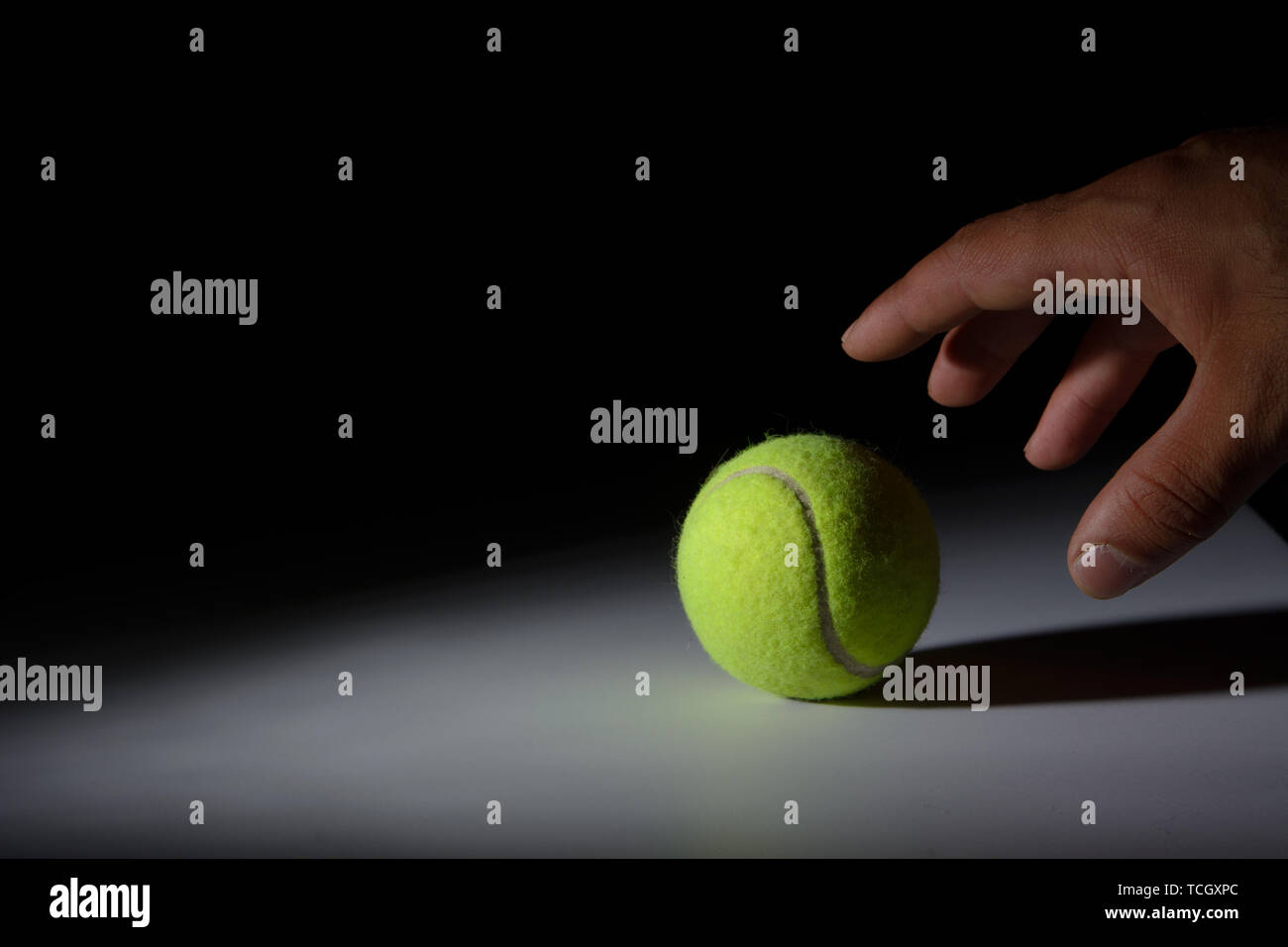 A tan male hand grabbing for a green tennis ball Stock Photo - Alamy