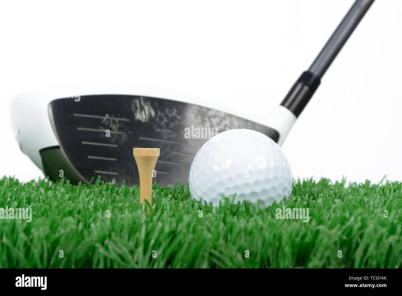 a driver golf club and a golf tee on the tall grass. the golf ball has ...