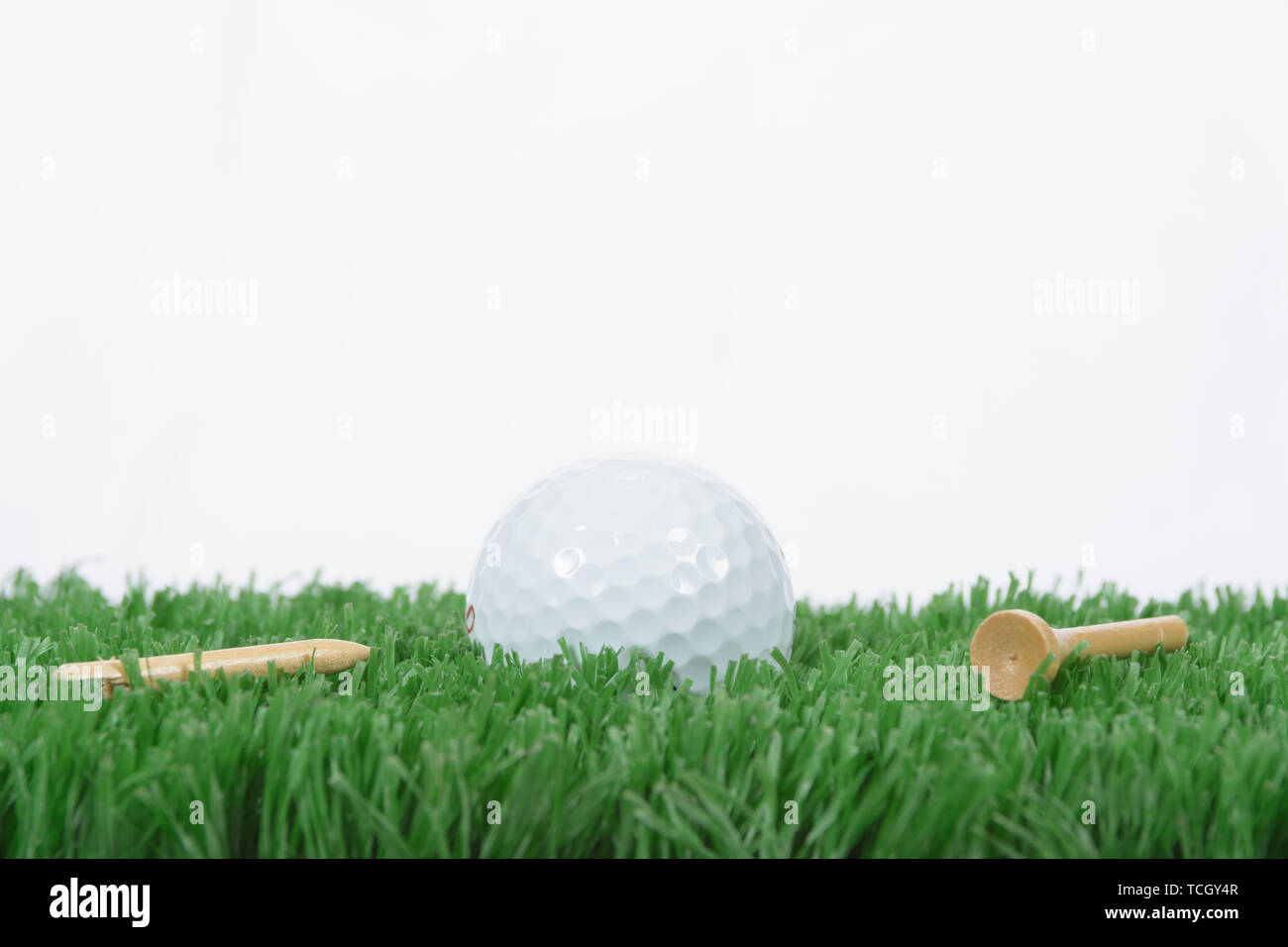A white golf ball sitting on the green rough grass with a white ...