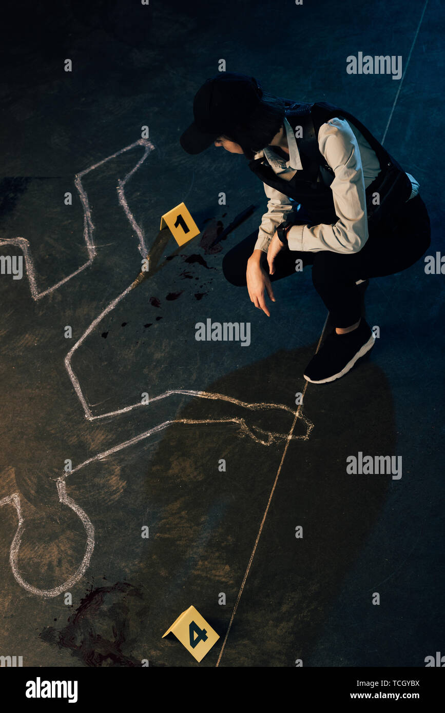 overhead view of investigator near chalk outline and evidence markers ...