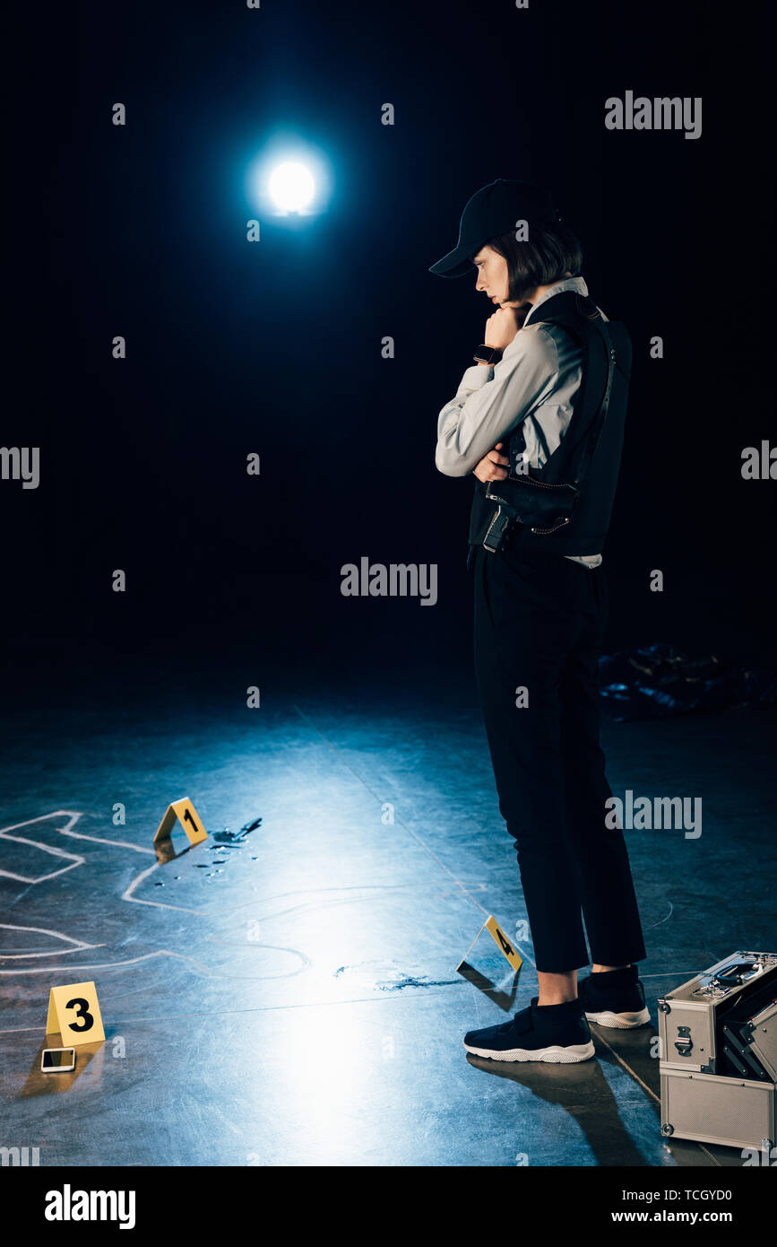 full length view of investigator looking at evidences at crime scene ...