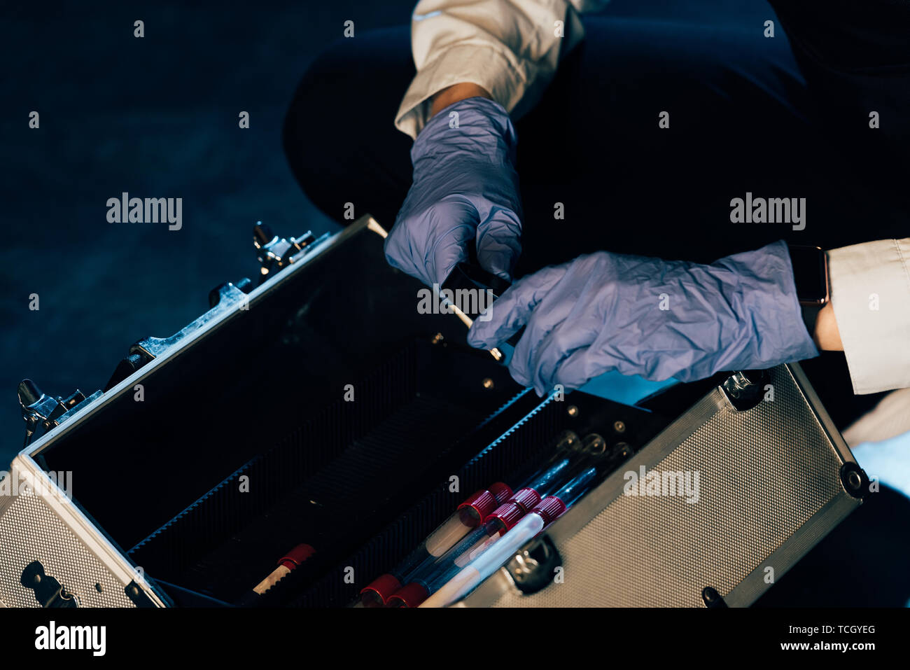 cropped view of investigator in rubber gloves with investigation kit at ...