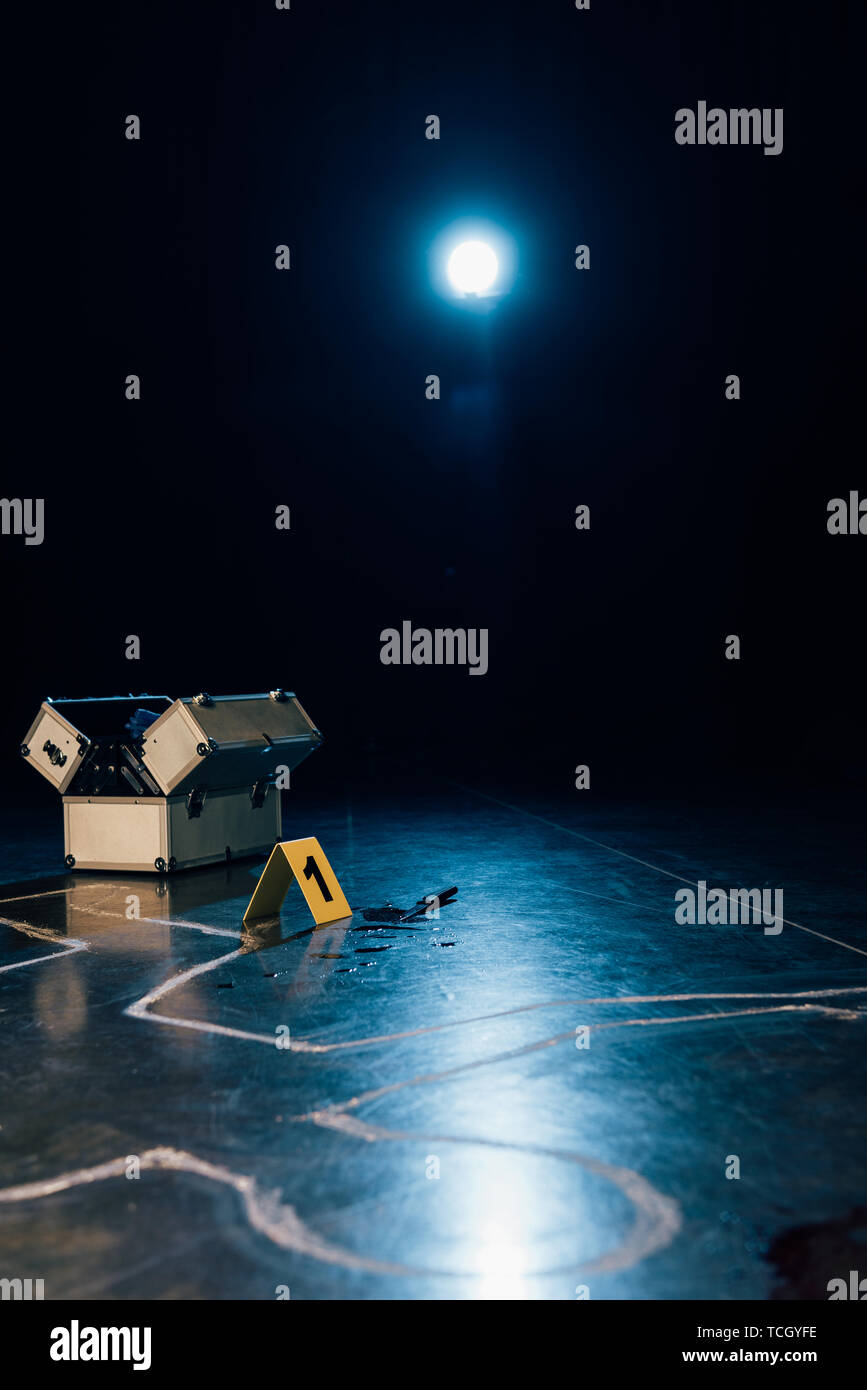 selective focus of chalk outline, investigation kit and evidence marker ...