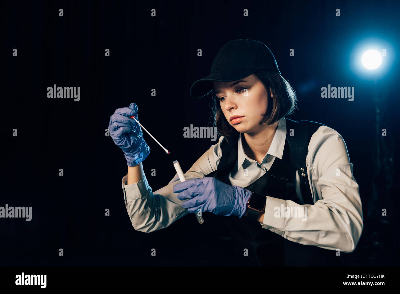 investigator in rubber gloves holding swab and test tube at crime scene ...