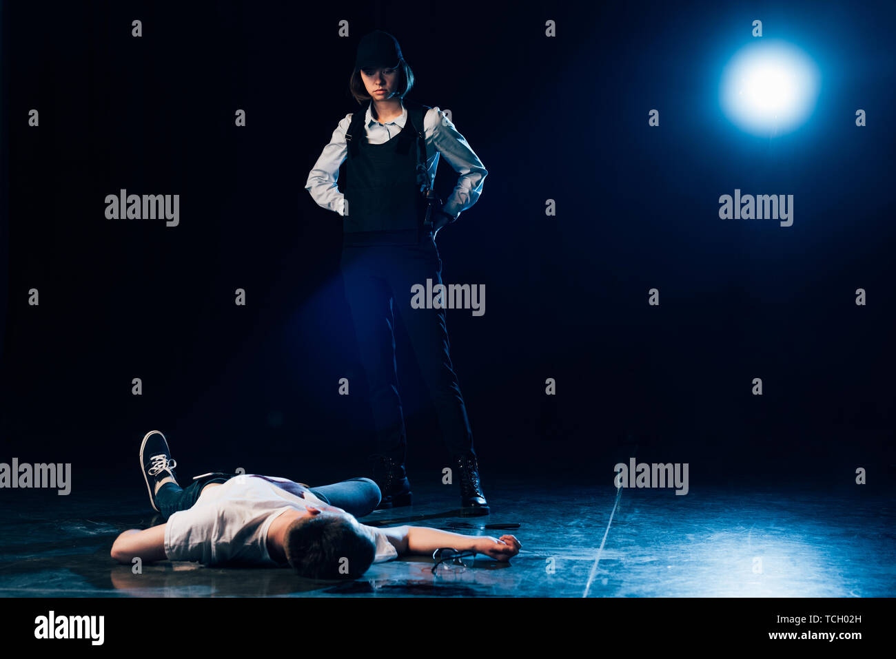 full length view of investigator in uniform standing near corpse at ...