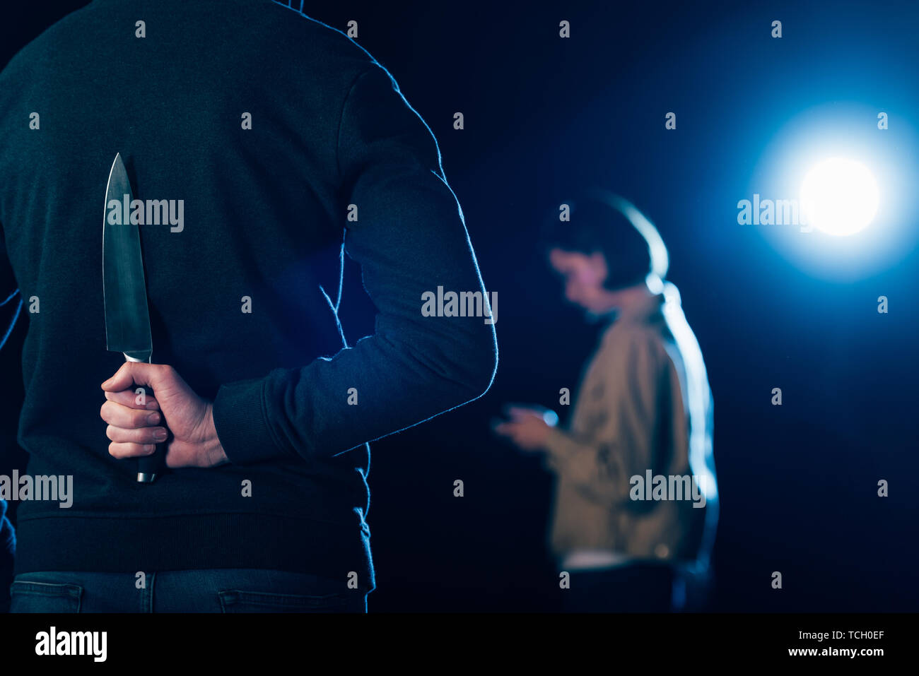 cropped view of murderer hiding knife behind back on black Stock Photo ...