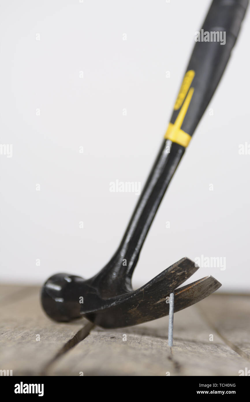 Hammer prying out a nail from a wood plank Stock Photo - Alamy
