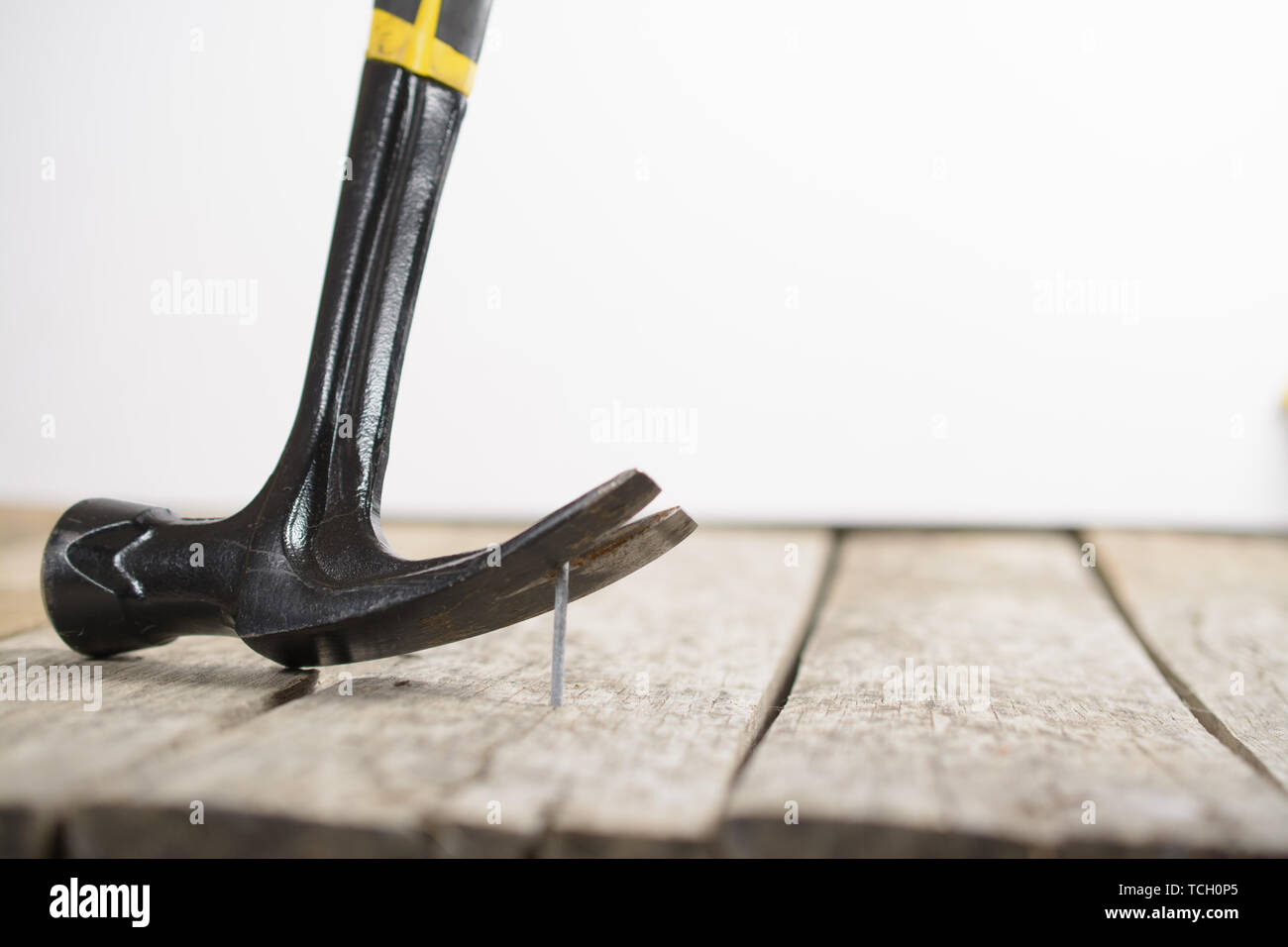 Hammer prying out a nail from a wood plank Stock Photo - Alamy