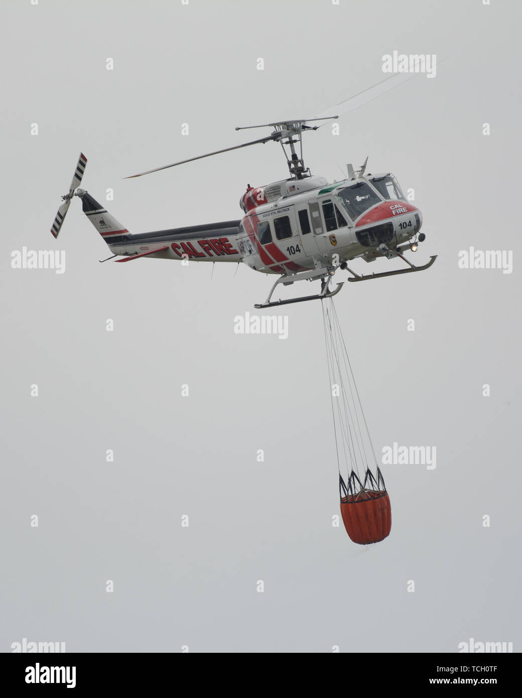 A Cal Fire helicopter flying around with water bucket in lake berryessa ...