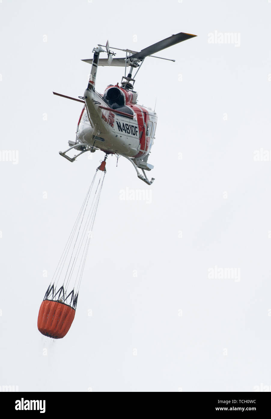 A Cal Fire helicopter flying around with water bucket in lake berryessa ...
