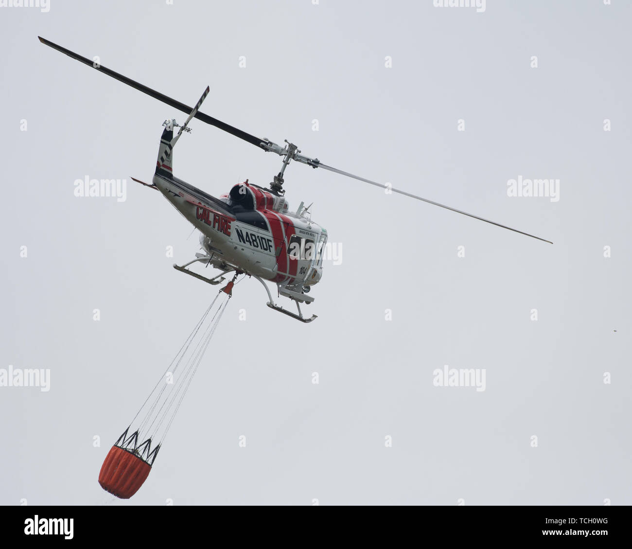 A Cal Fire helicopter flying around with water bucket in lake berryessa ...