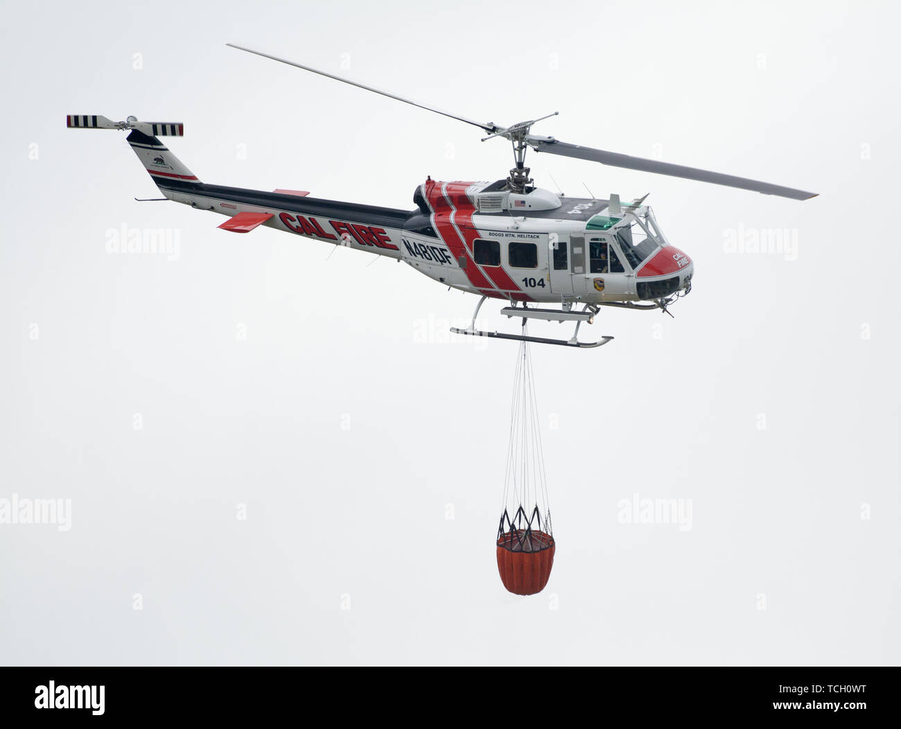 A Cal Fire helicopter flying around with water bucket in lake berryessa ...