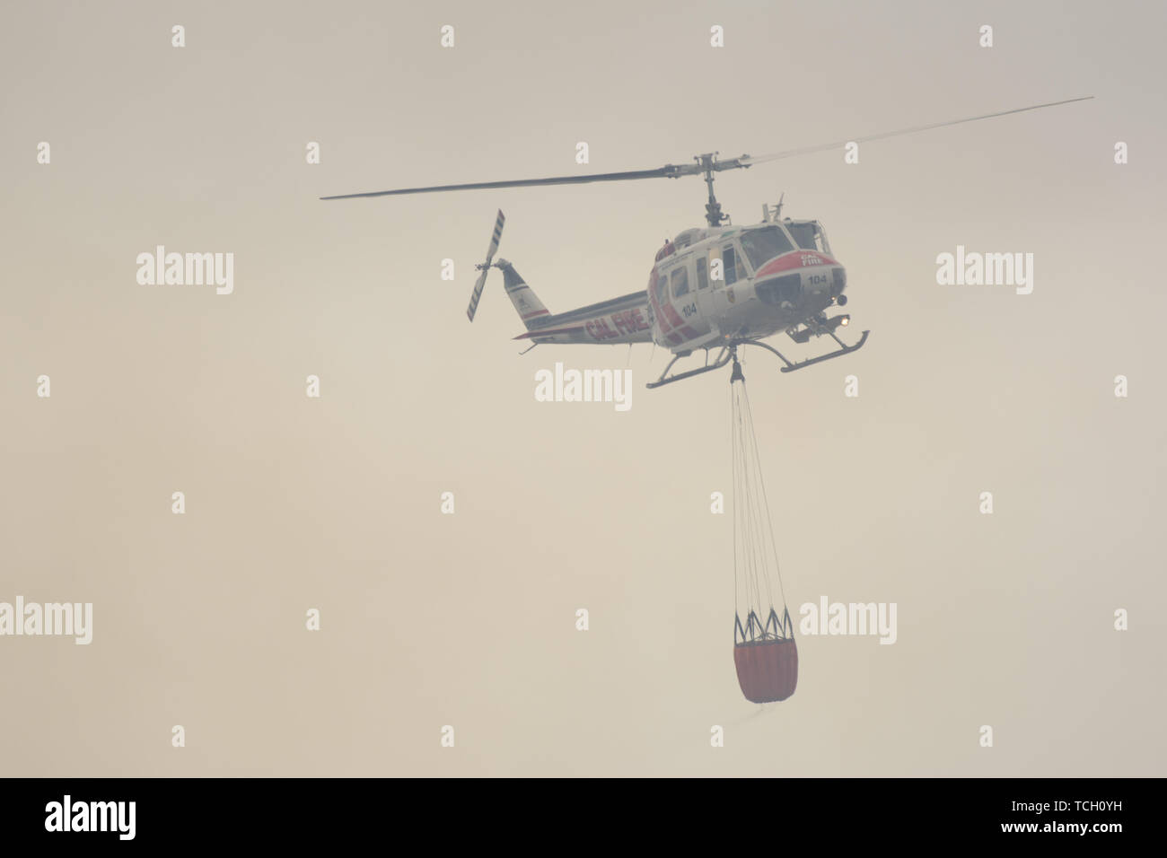 A Cal Fire helicopter flying around with water bucket in lake berryessa ...