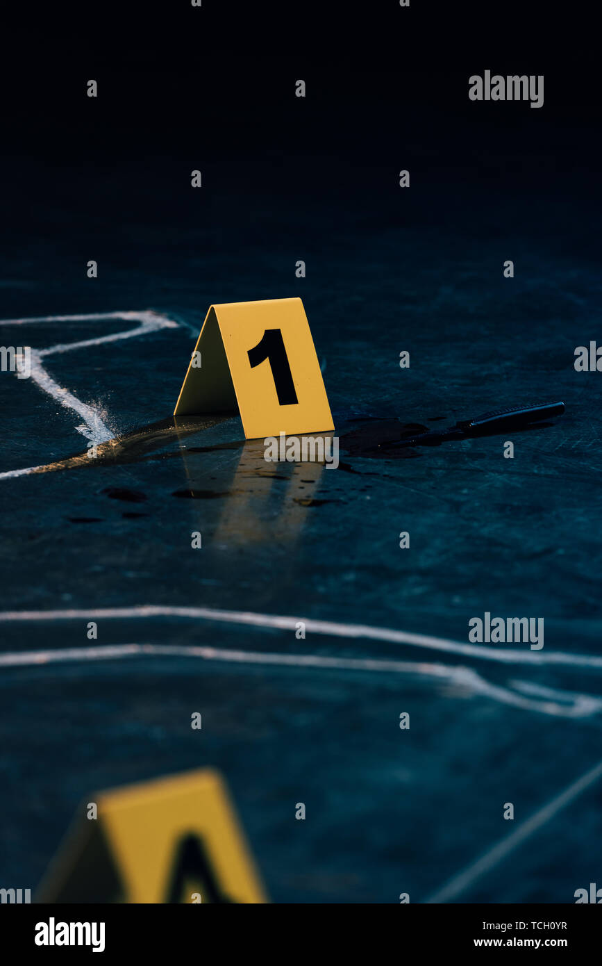 selective focus of chalk outline and evidence markers at crime scene ...