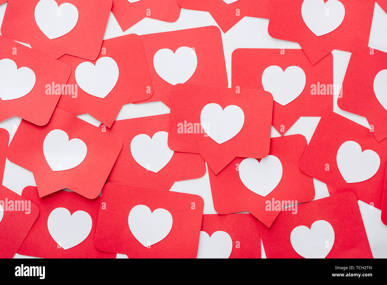top view of red paper cut cards with hearts symbols on white surface ...