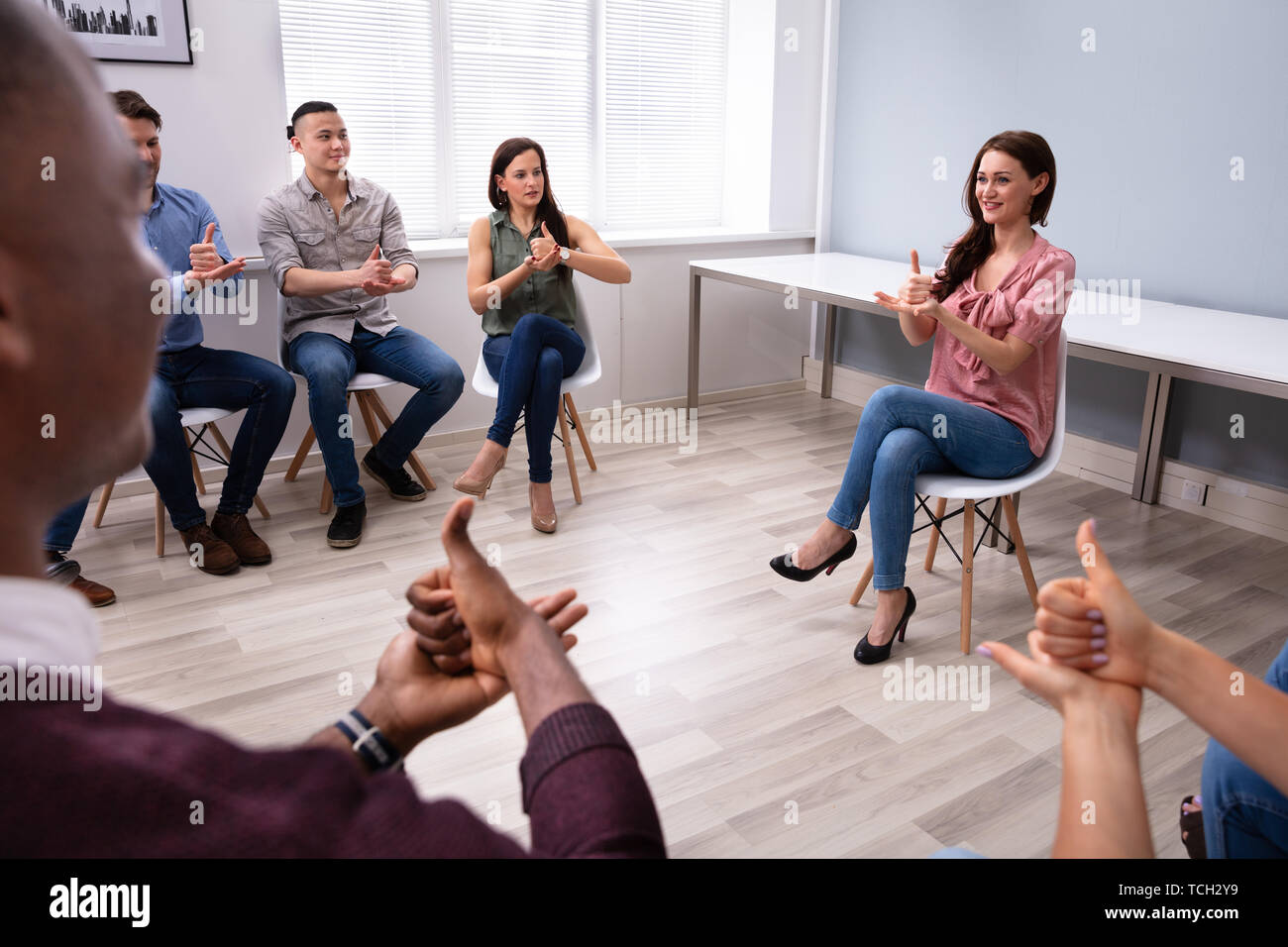 Group Of Young People Learning Deaf Gesture Sign From Woman Sitting On ...