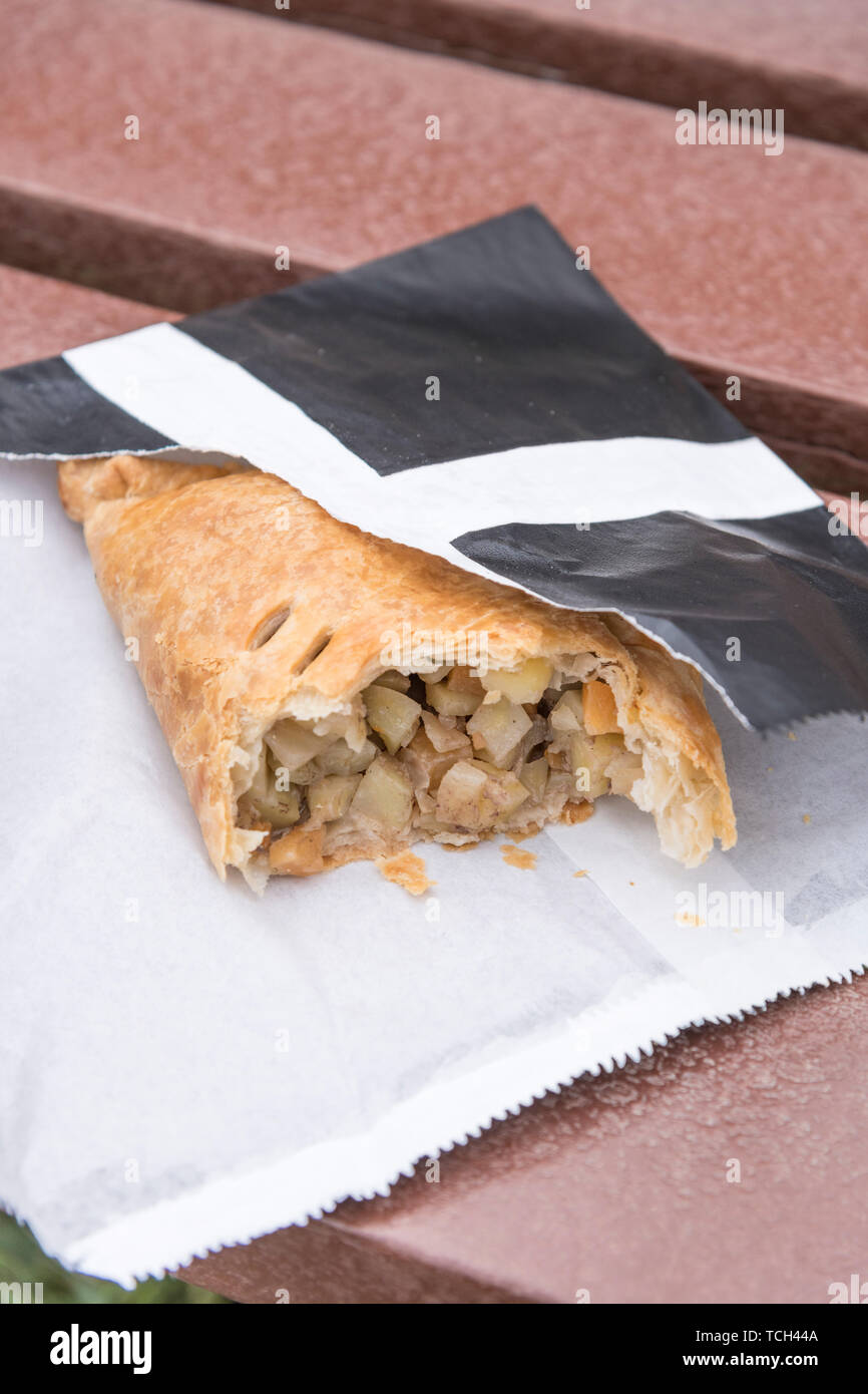 Cornish pasty sitting on paper food bag decorated with St. Piran's flag ...