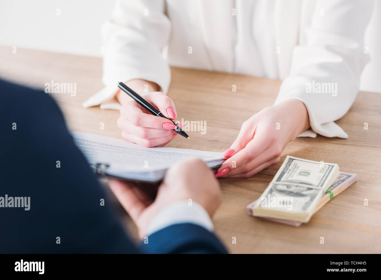 cropped shot of woman signing contract on clipboard in hands of manager ...